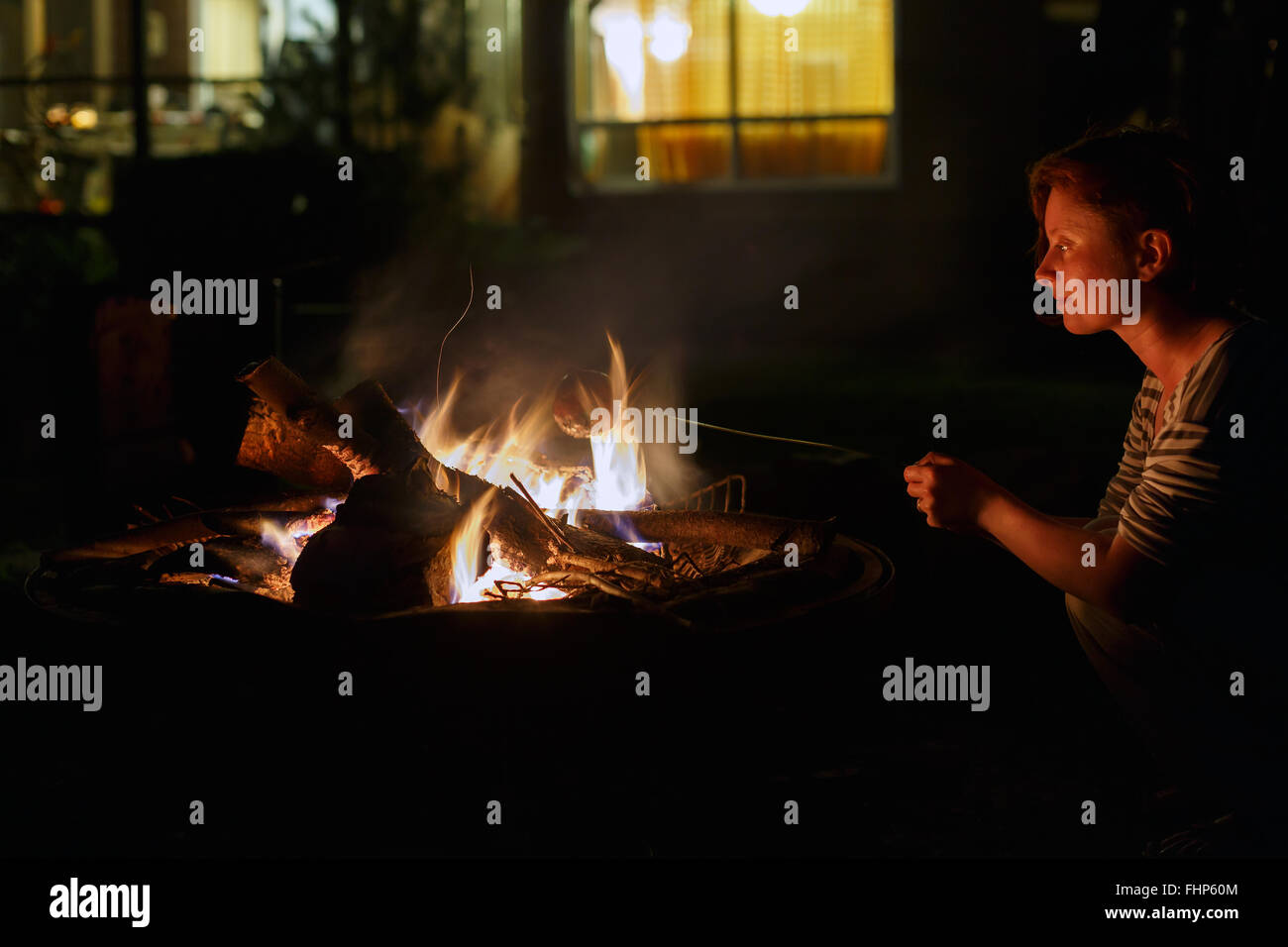 Young woman bakes apple on bonfire at night Stock Photo - Alamy