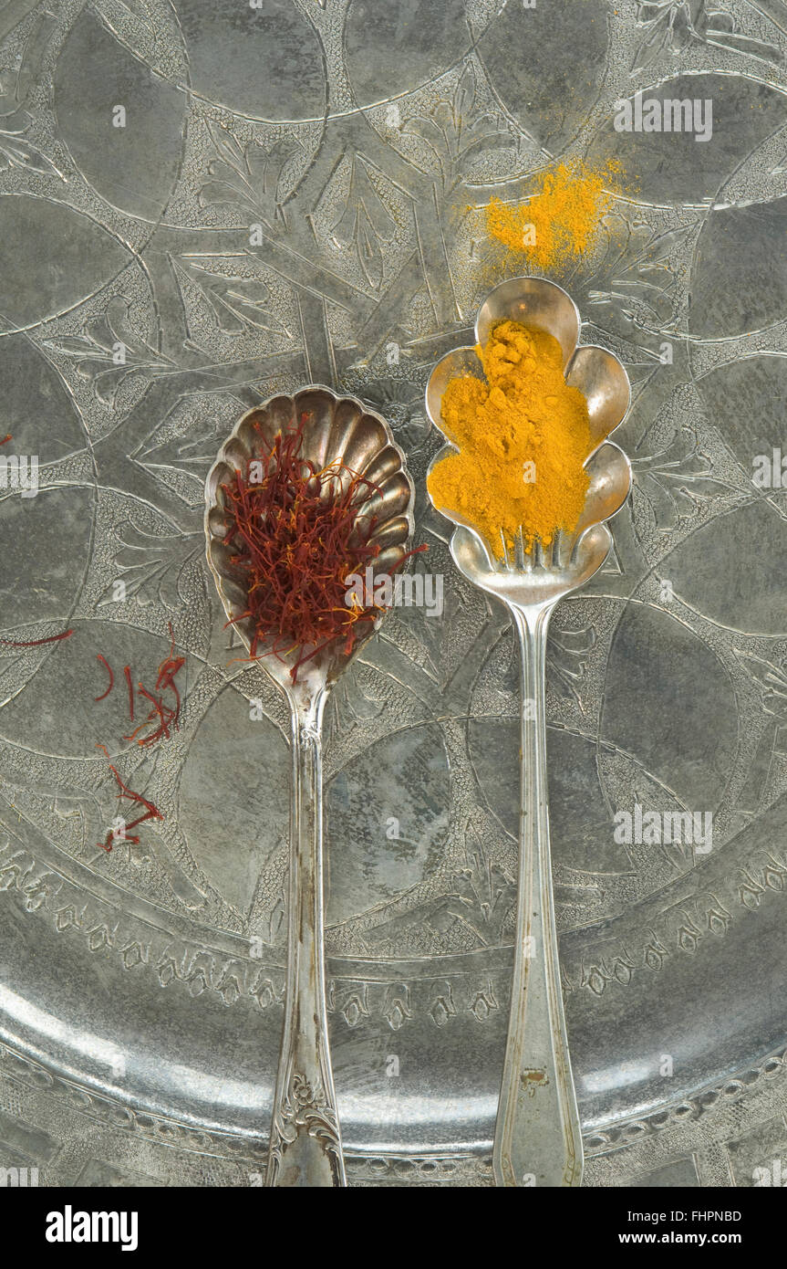 Silver spoons of ground saffron and saffron threads on silver tray ...