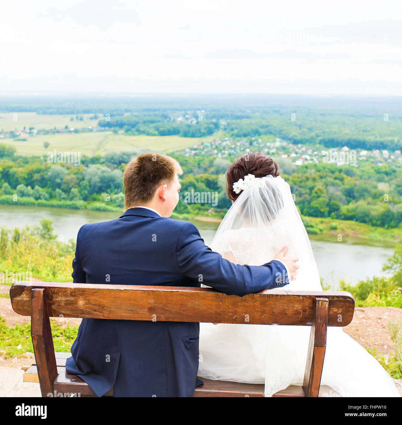 Romantic wedding couple sitting on a bench in the park Stock Photo - Alamy