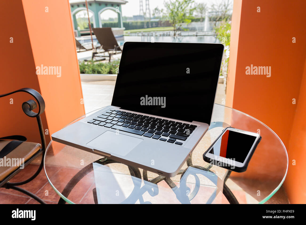 Laptop computer, phone ,books and plant on the table in swimming pool ...