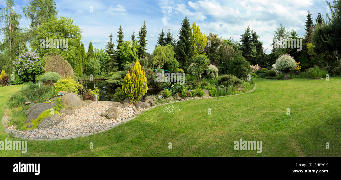 Beautiful spring garden design, with conifer trees, green grass and ...