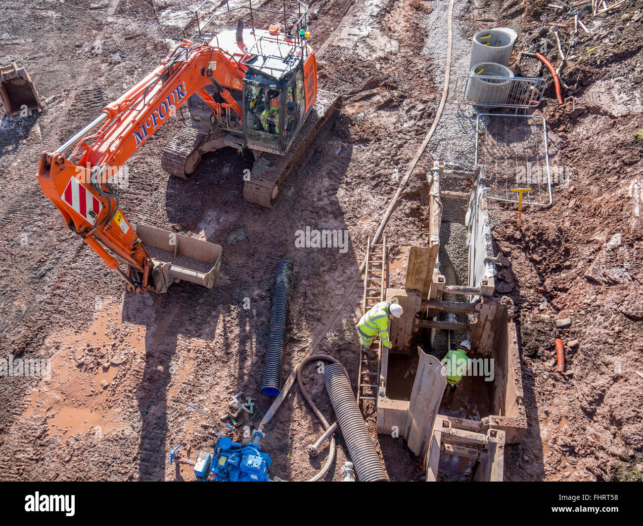 Digger and construction workers filling in a hole after laying new ...