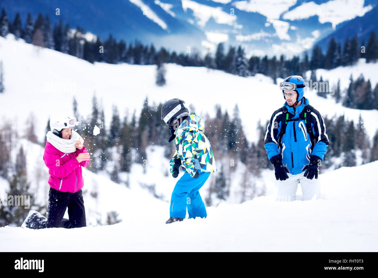 Young happy family with one child, skiing in the mountains, wintertime ...