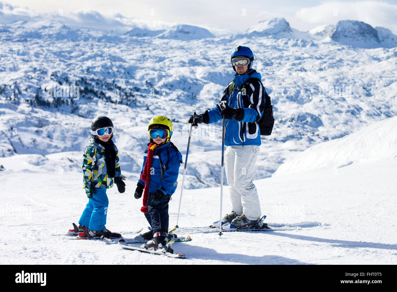 Father and two boys, skiing on a sunny day on a mountain summit in ...