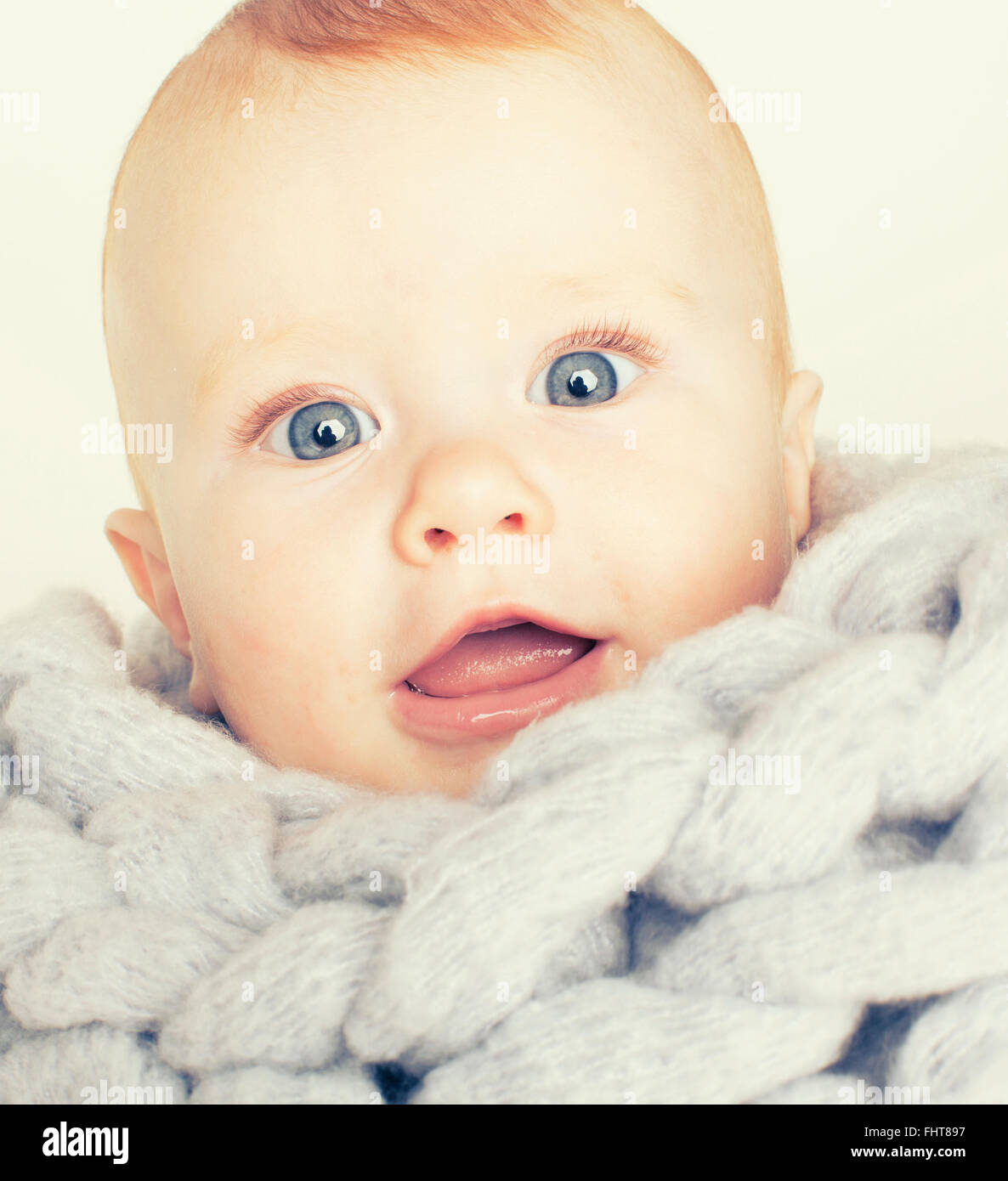 little cute red head baby in scarf all over him close up isolated ...