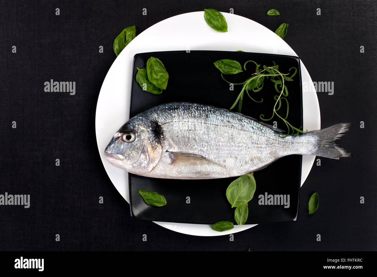 Fish on plate with fresh herbs, top view Stock Photo - Alamy
