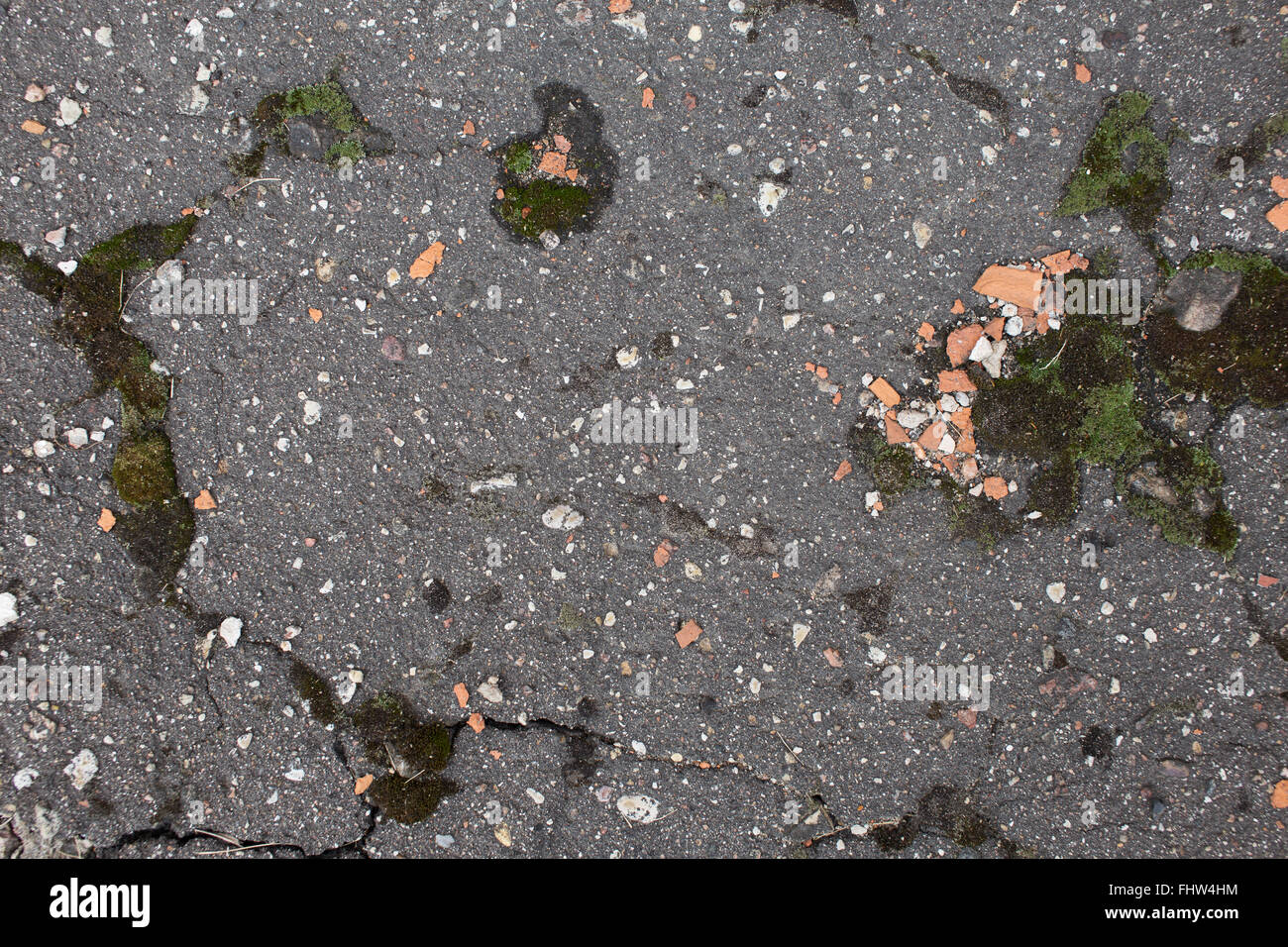 Weathered asphalt texture with pieces of broken bricks and moss Stock ...