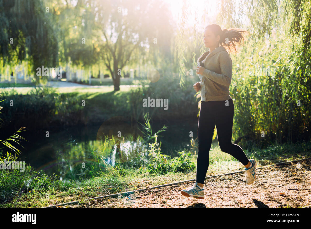 Fit female jogger running in nature surrounded by beautiful hanging ...