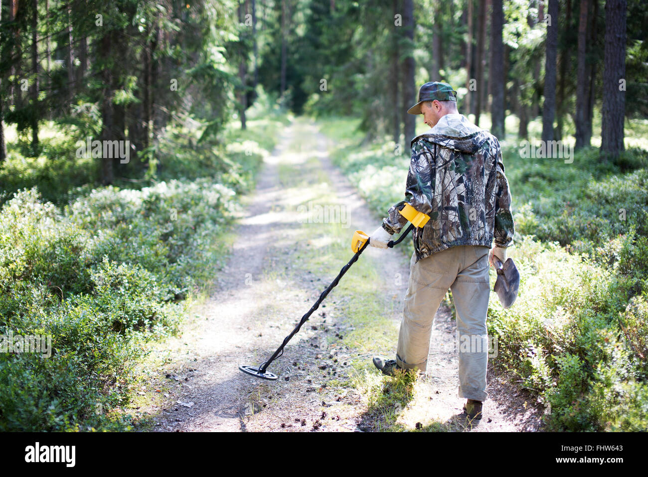 Treasure hunter with metal detector and shovel in forest Stock Photo ...