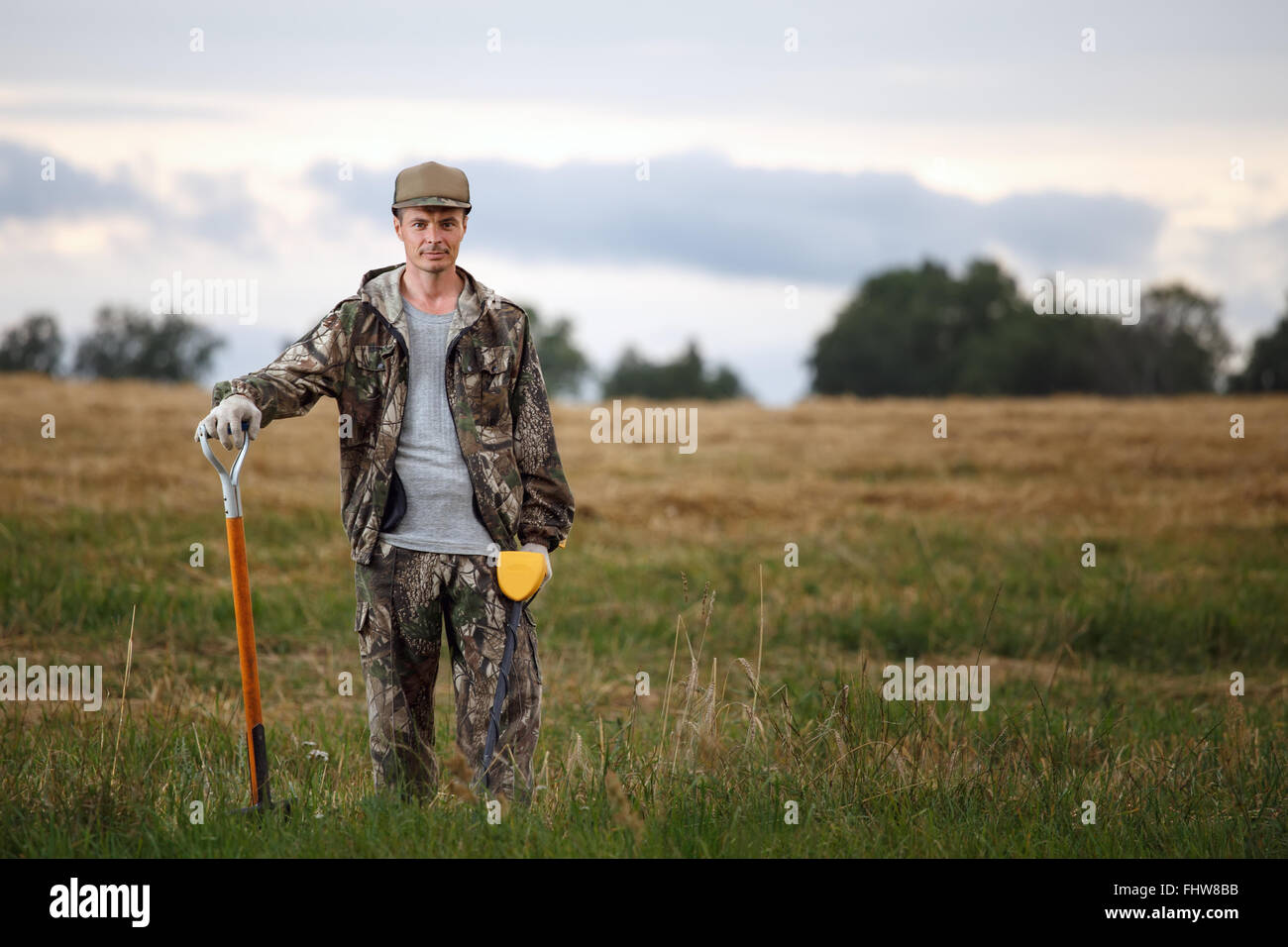 Man with metal detector and shovel posing in the field. Treasure hunter ...