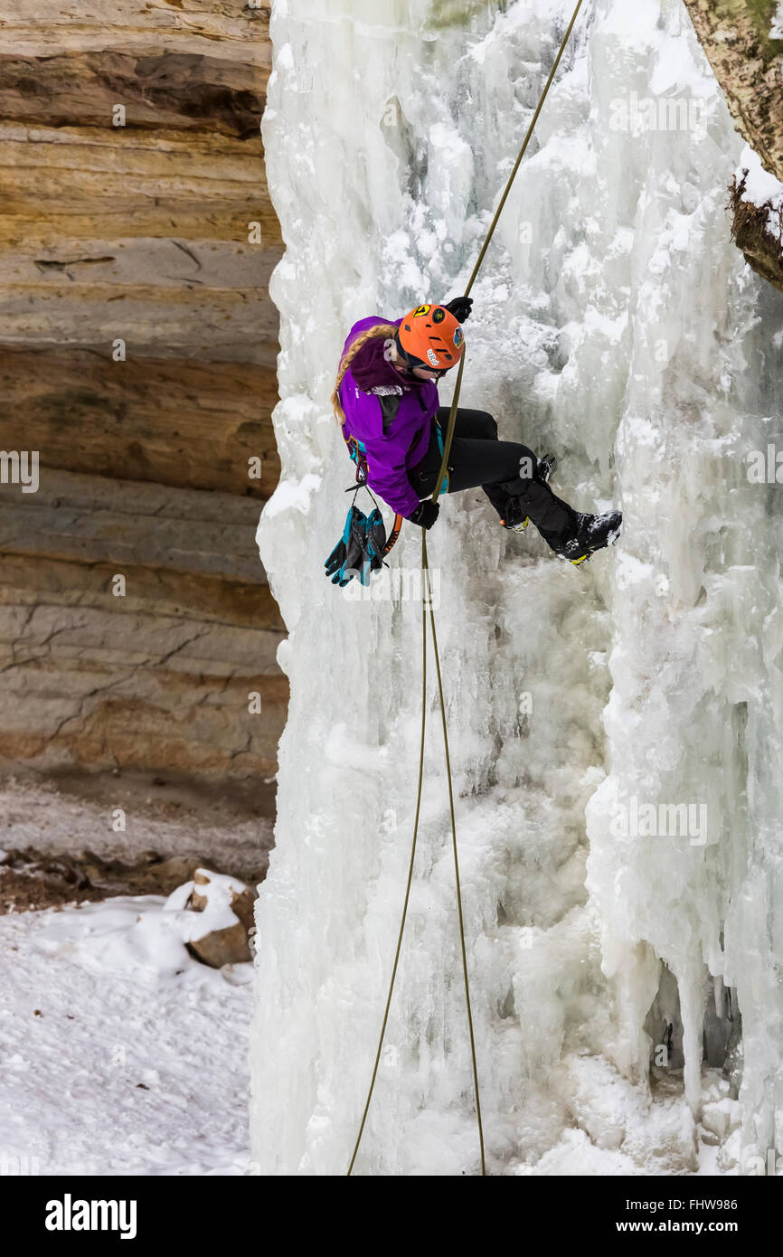 Woman ice climber rappelling down a frozen waterfall in Pictured Rocks ...