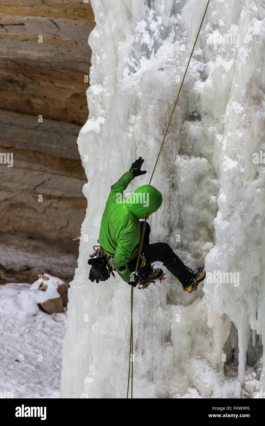 Ice climber rappelling down a frozen waterfall in Pictured Rocks ...