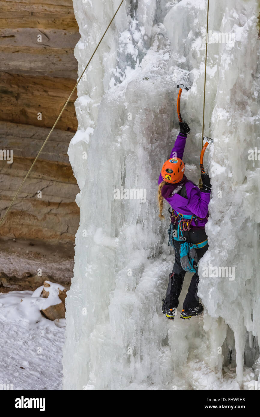 Woman ice climber ascending a frozen waterfall in Pictured Rocks ...