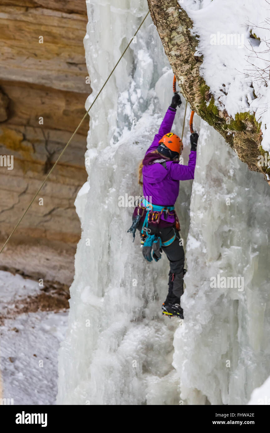 Woman ice climber ascending a frozen waterfall in Pictured Rocks ...