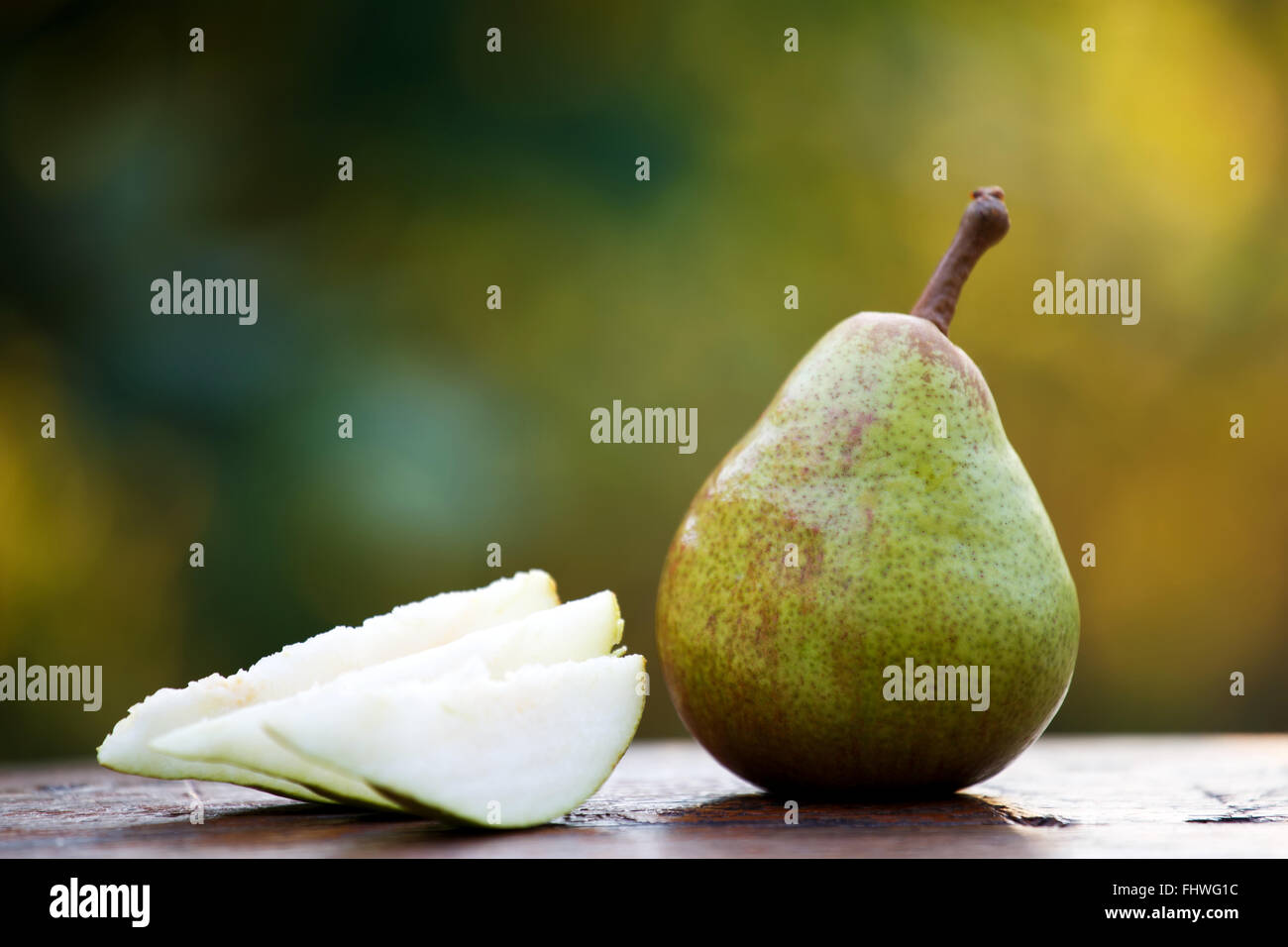 Homegrown organic pear with cut slices on rustic wood. Creamy bokeh and ...