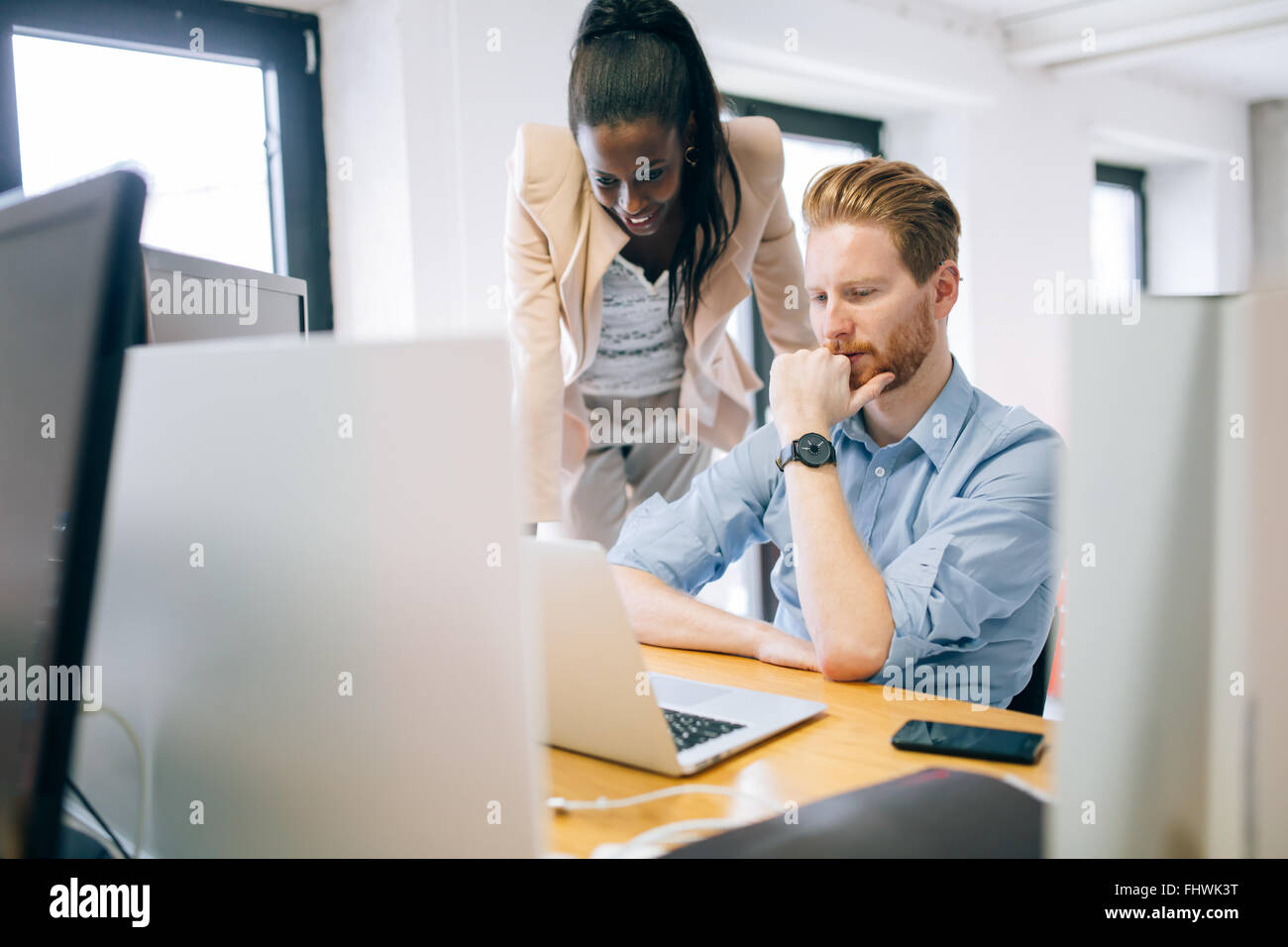 Supervising colleague during work in office Stock Photo - Alamy