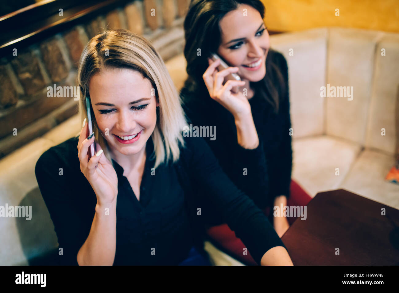 Two beautiful women talking on phone in cafe while being happy Stock ...