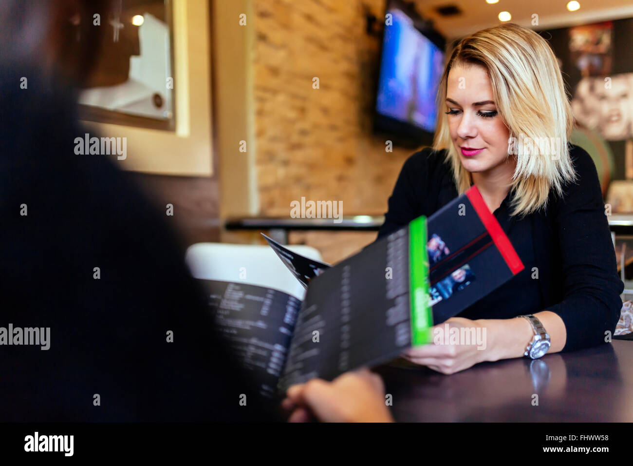Two women looking at menu before ordering at cafe Stock Photo - Alamy