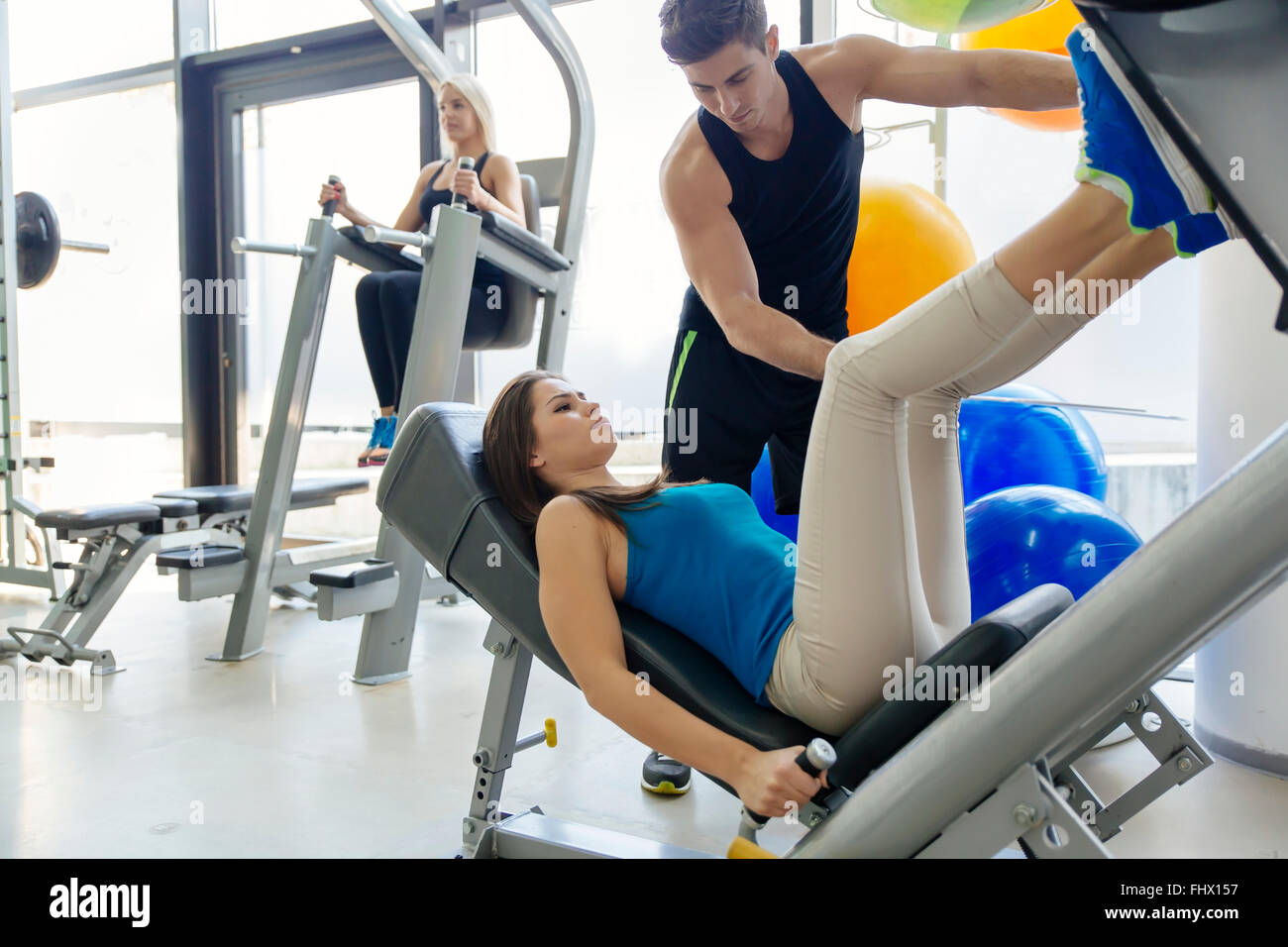 Beautiful woman doing leg exercises in gym with the help of personal ...