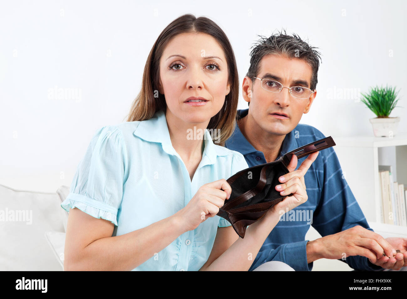 Elderly couple showing empty wallet in living room Stock Photo - Alamy
