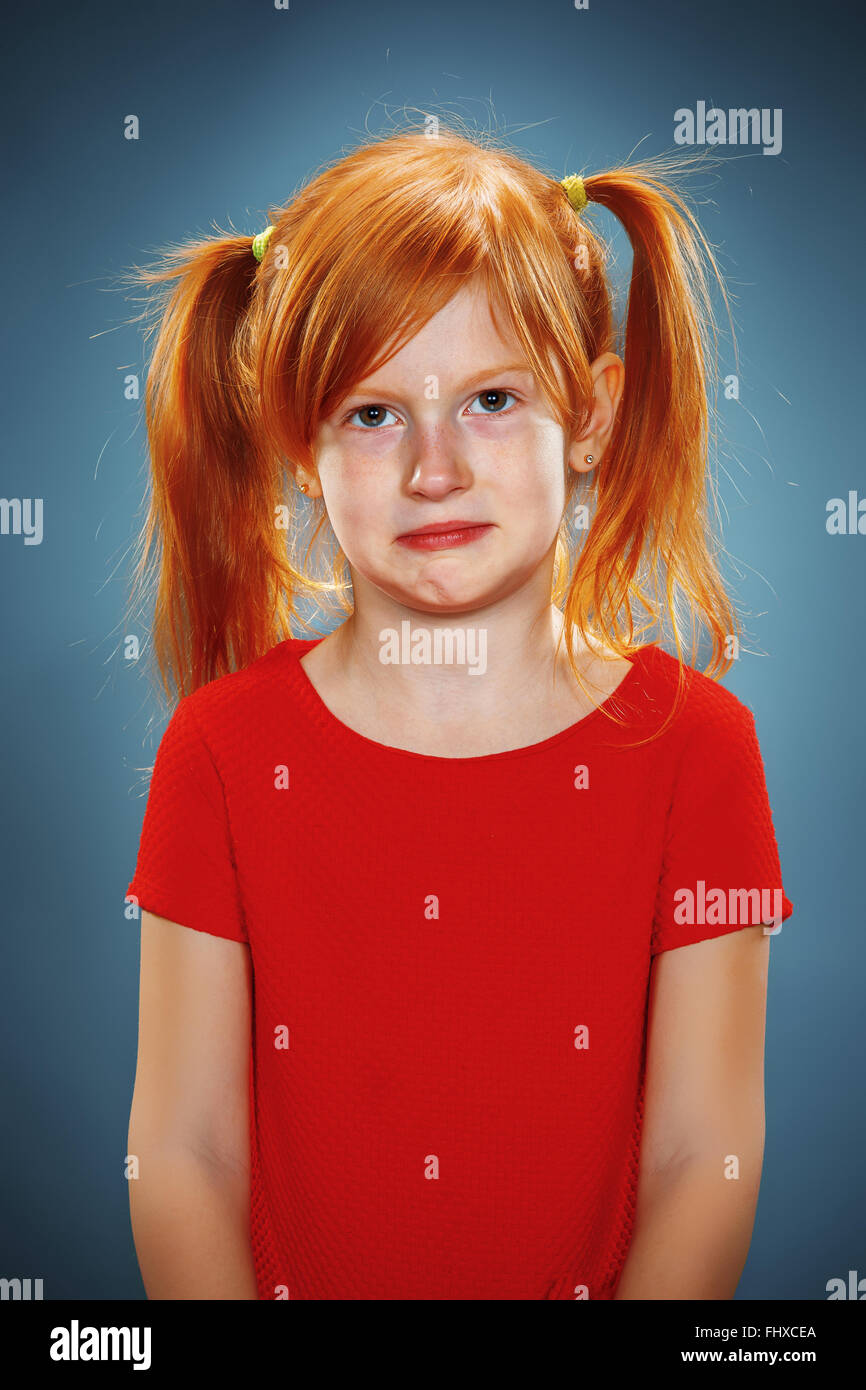 The beautiful portrait of a thoughtful little girl with red hair in red ...