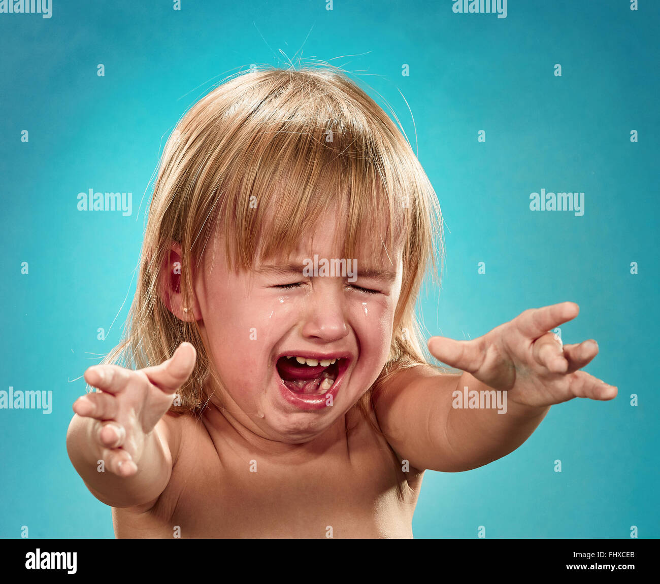 The portrait of a little girl. She is crying on blue background Stock ...