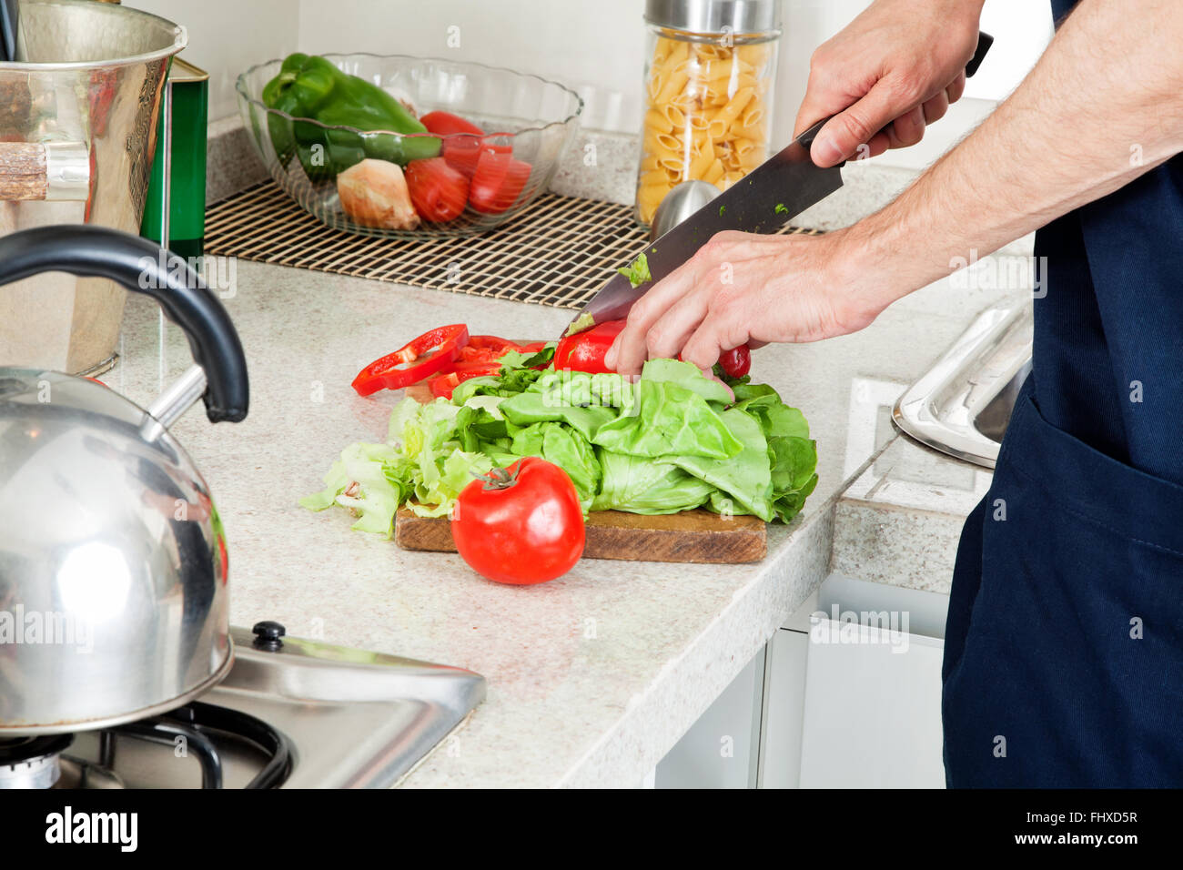 Man cutting vegetables on small board in kitchen with knife Stock Photo ...