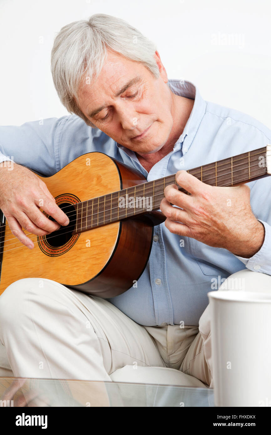 Elderly man on couch playing acoustic guitar Stock Photo - Alamy