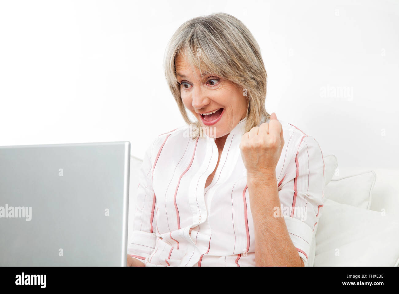 Happy senior woman cheering while looking at computer Stock Photo - Alamy