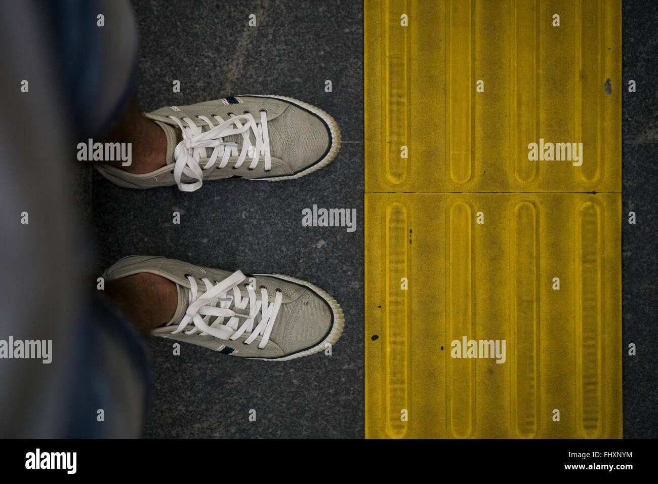 Feet of a man standing in front of a yellow hazard warning line Stock ...