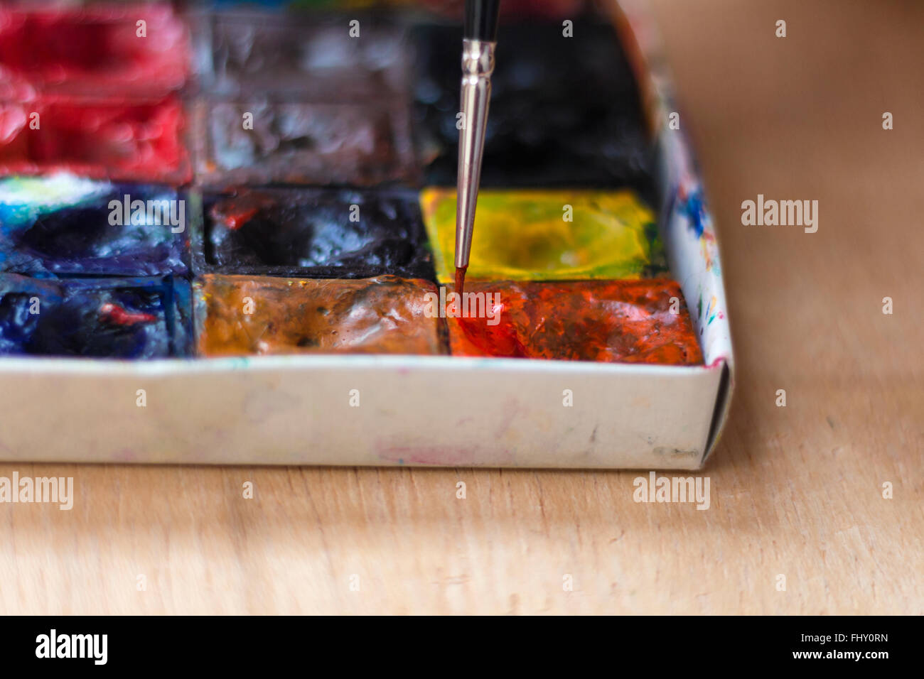 Loading a brush with orange watercolor paint Stock Photo - Alamy