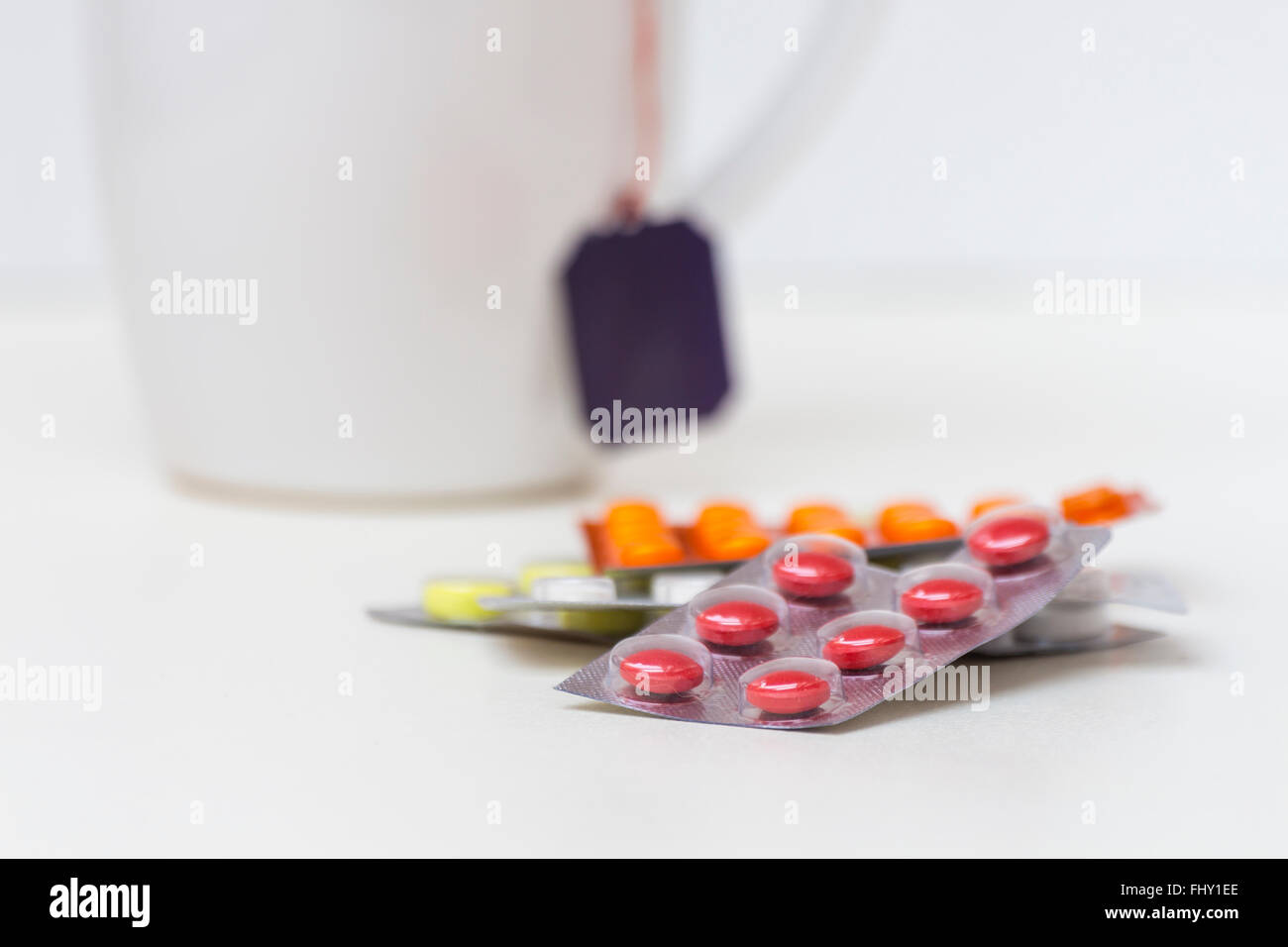 Red medication and a cup of tea in the background Stock Photo - Alamy