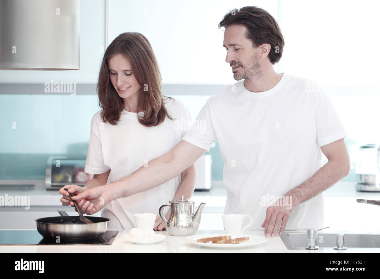 Happy couple cooking breakfast together in the kitchen Stock Photo - Alamy