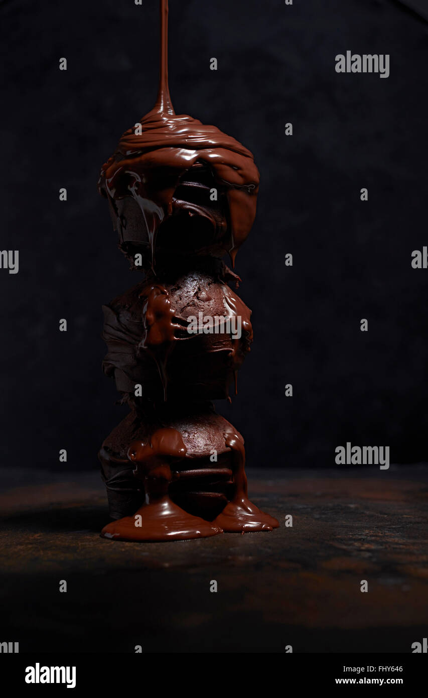 Liquid chocolate dripping on stack of three chocolate muffins Stock ...