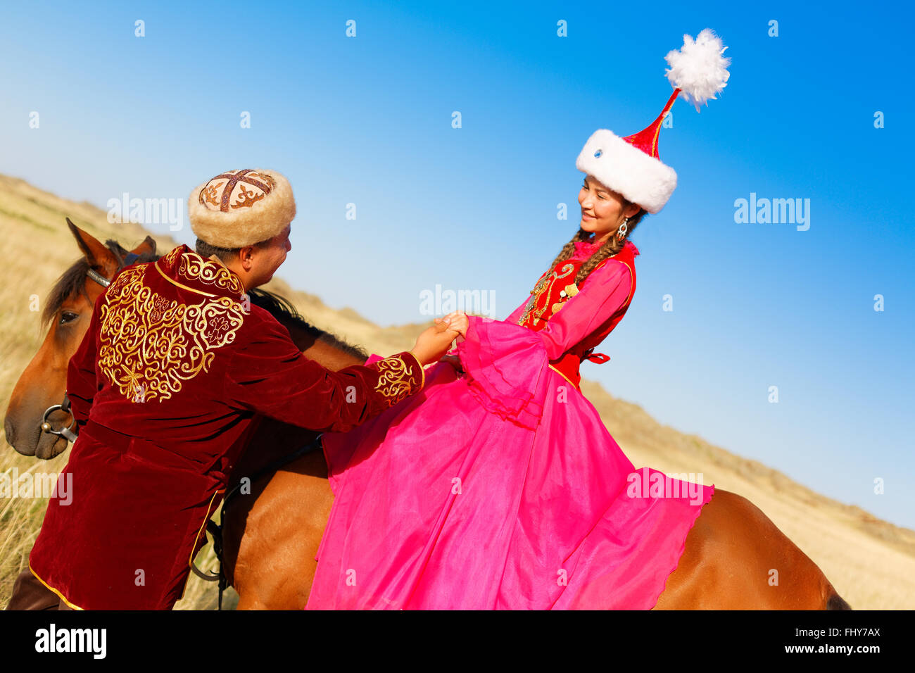 kazakh man and woman in national costumes in the steppe riding a horse ...