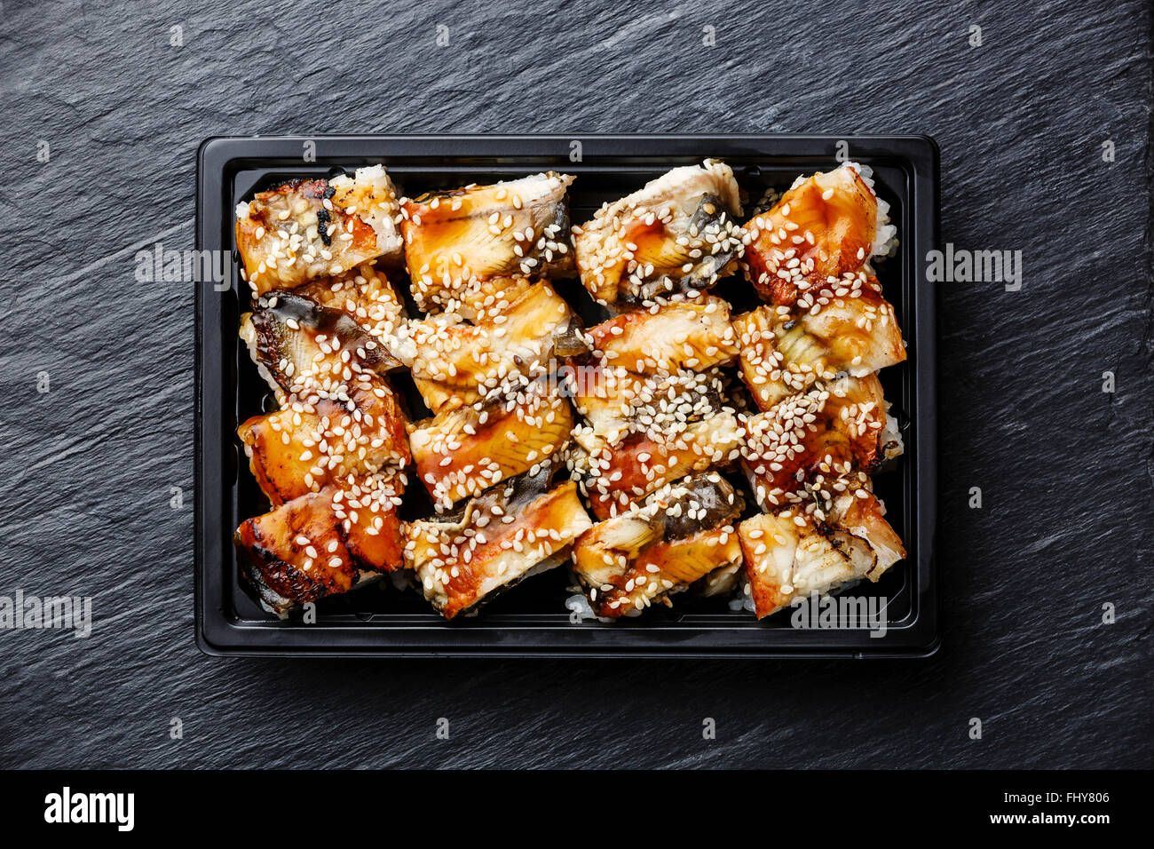 Eel Sushi rolls in plastic box packaging tray on black stone slate ...