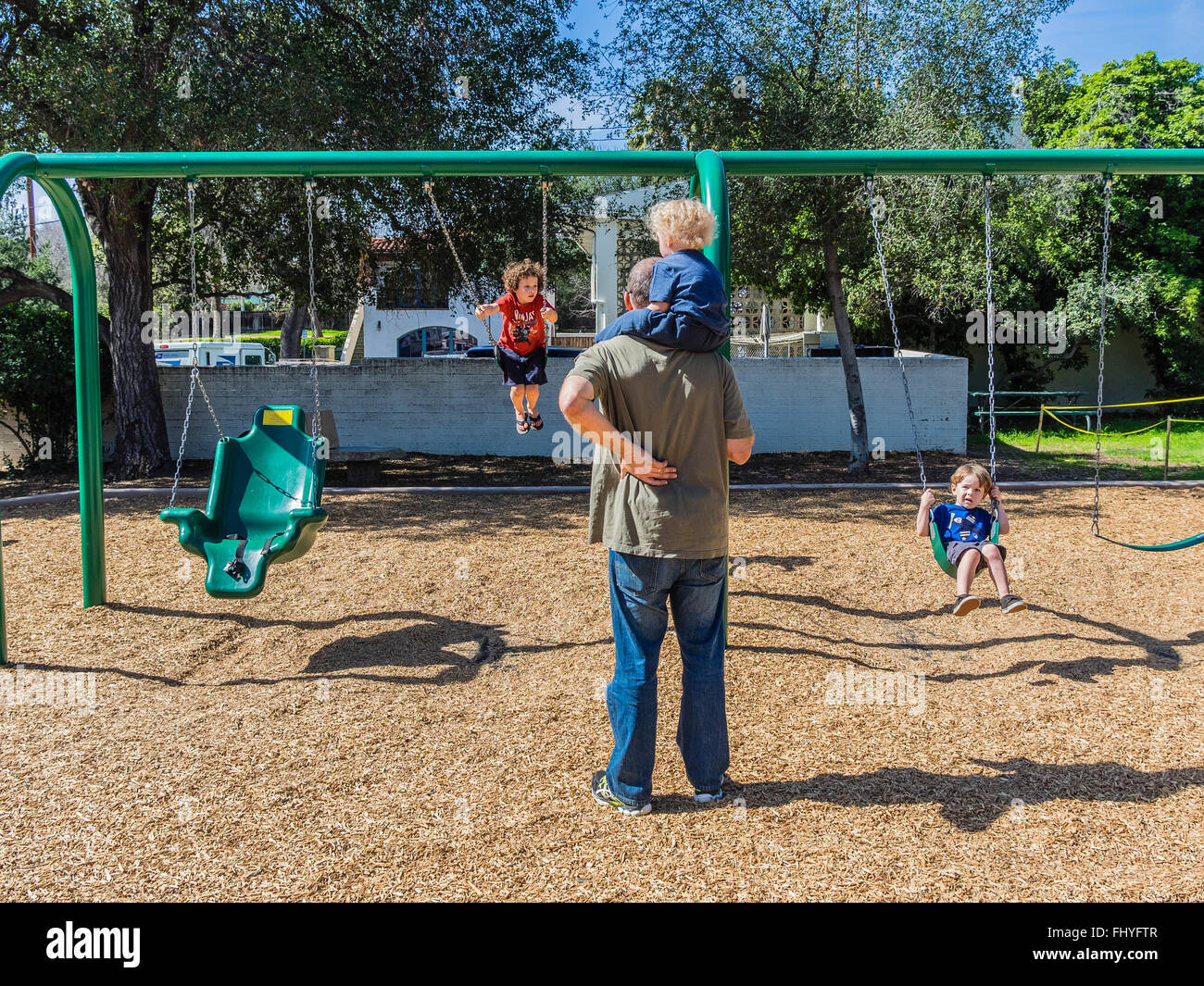 Four young kids having fun on a giant swing set that an adult female is ...