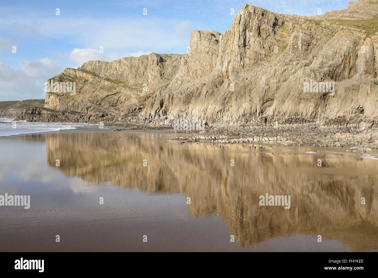Sea cliffs reflected in the wet beach of Mewslade Bay on the Gower ...