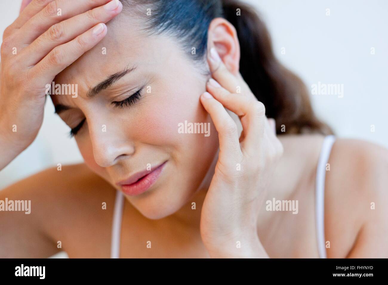 MODEL RELEASED. Woman touching her head and ear with earache Stock ...