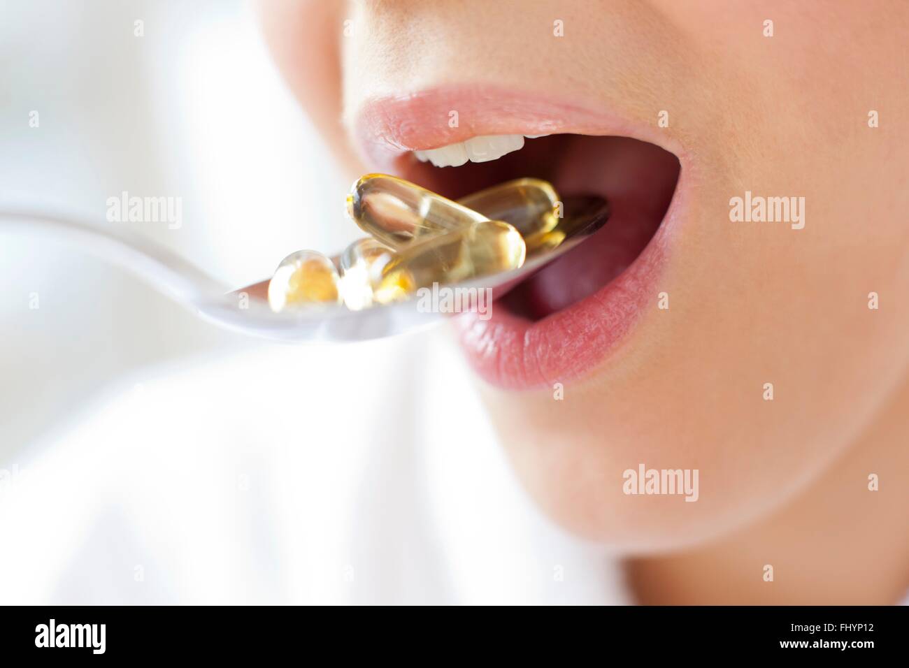 MODEL RELEASED. Woman taking vitamin supplements on a spoon Stock Photo ...