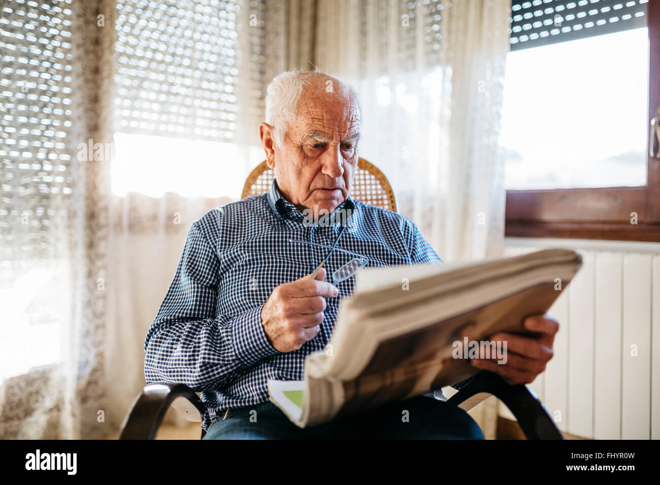 Senior man reading newspaper at home Stock Photo - Alamy