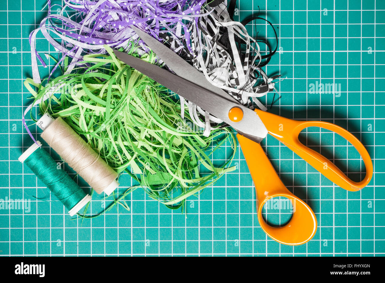 Textile offcuts, threads and scissors on checkered rotary cut mat Stock ...