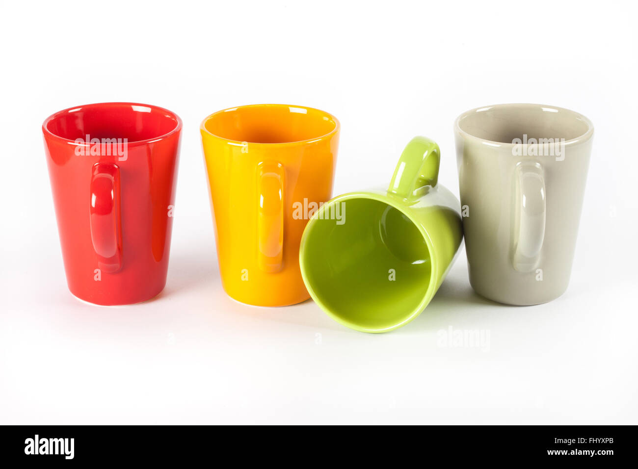 Four color tea cups shown in row, one overturned Stock Photo - Alamy