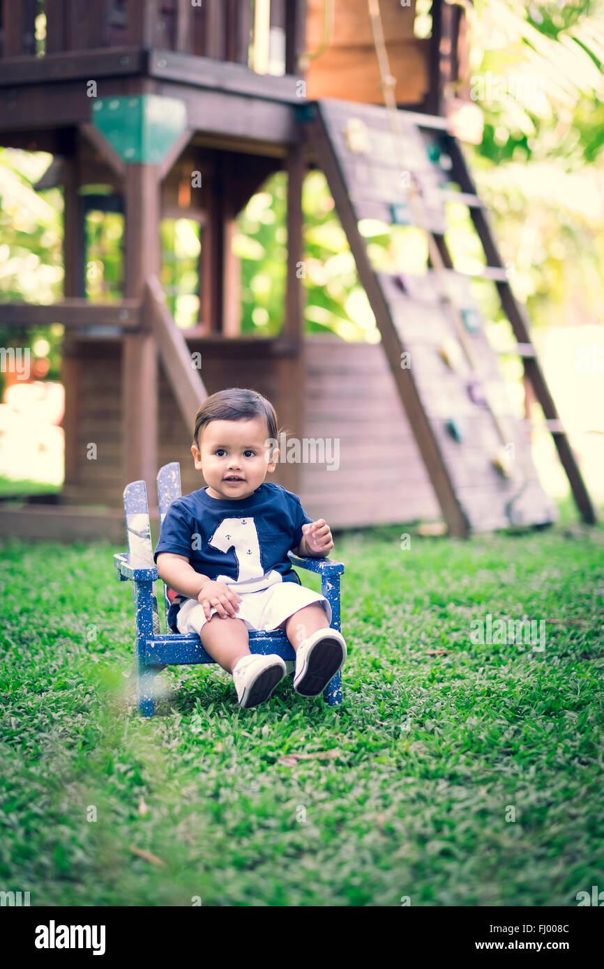 Baby boy sitting on chair on a meadow of a playground Stock Photo - Alamy
