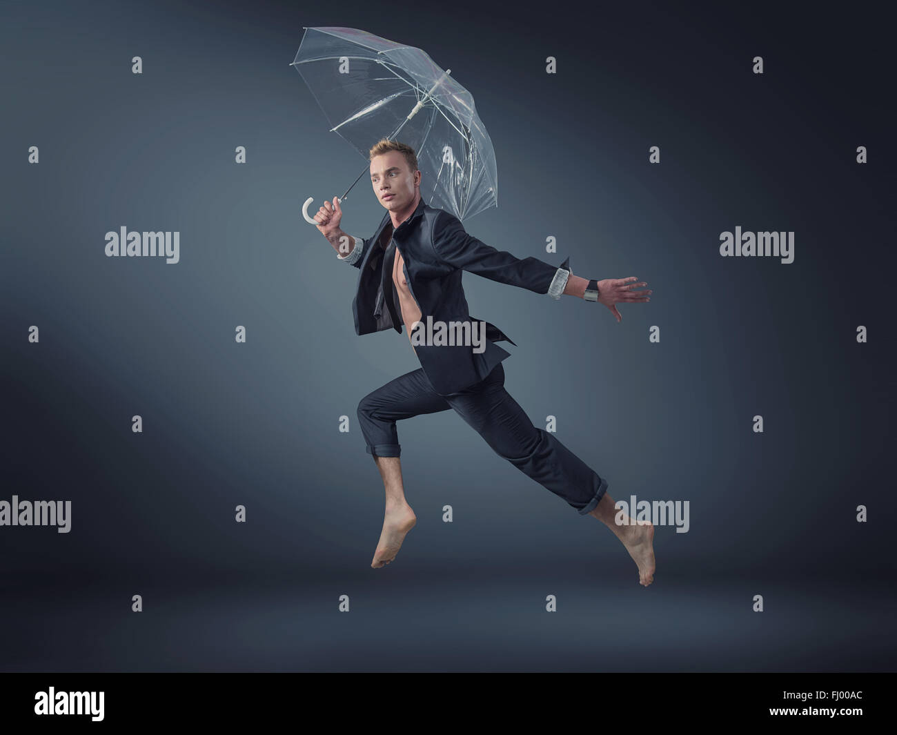 Handsome manager jumping with a transparent umbrella Stock Photo - Alamy
