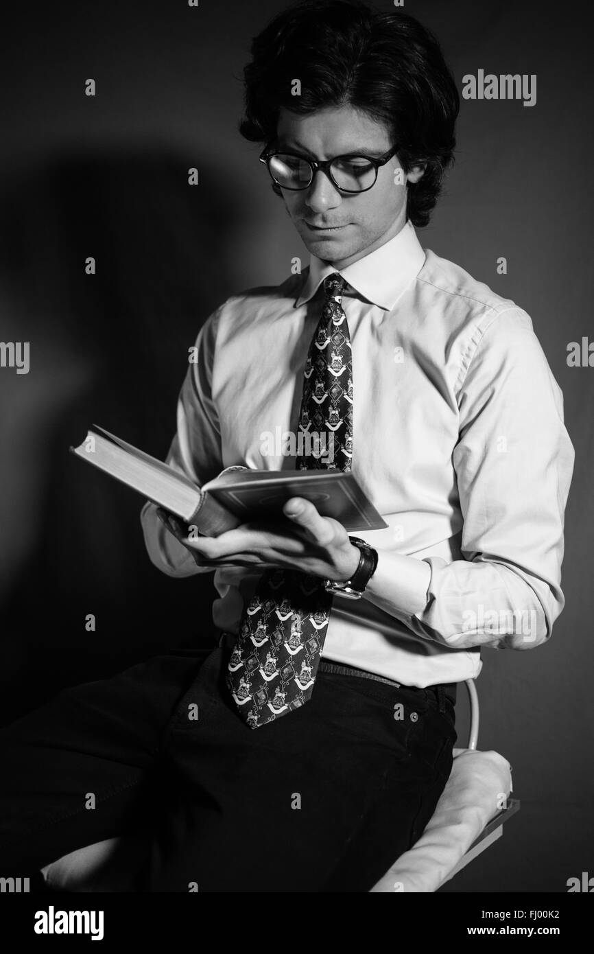 Young man reading a book with glasses Stock Photo - Alamy