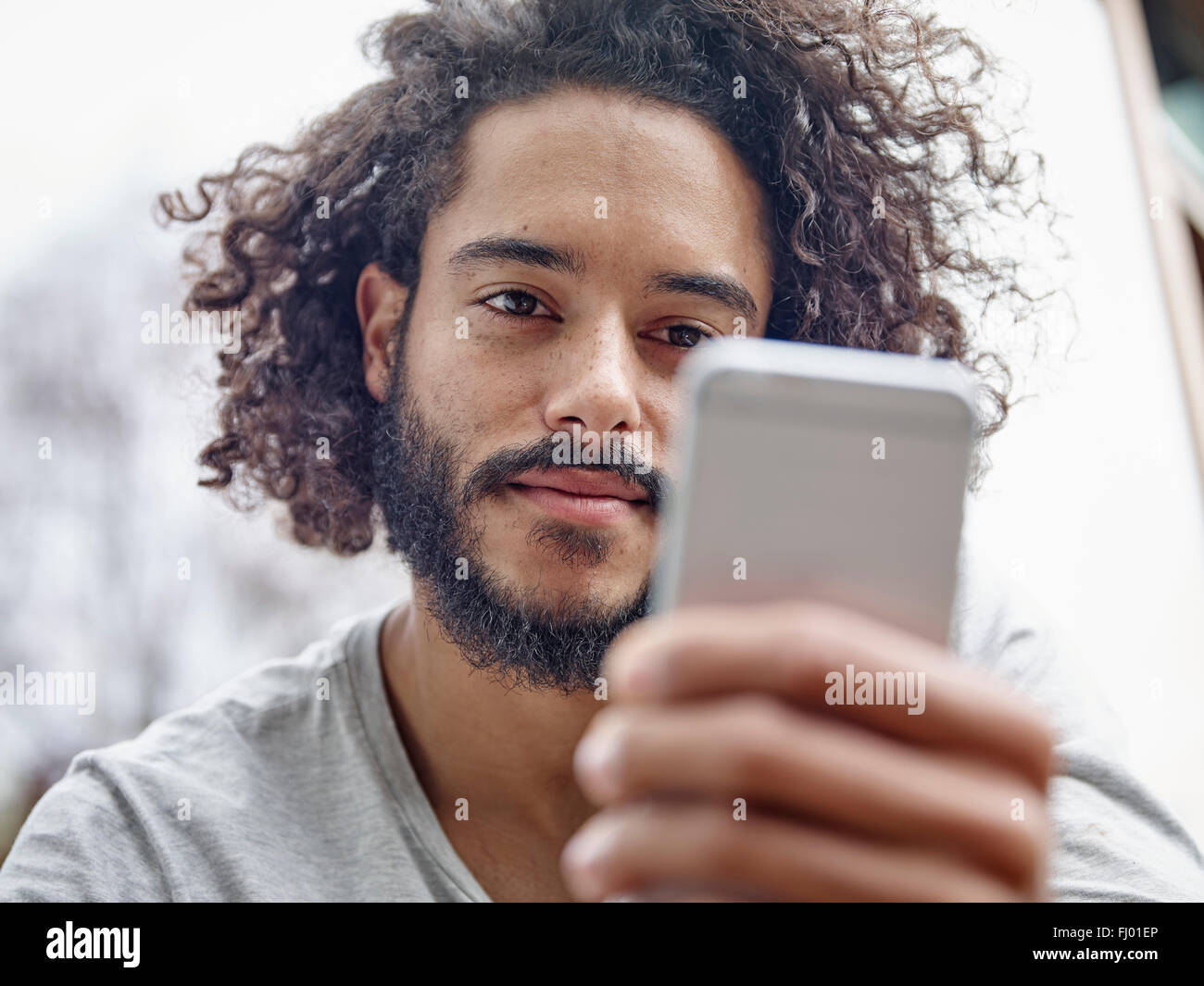Young man looking at cell phone Stock Photo - Alamy
