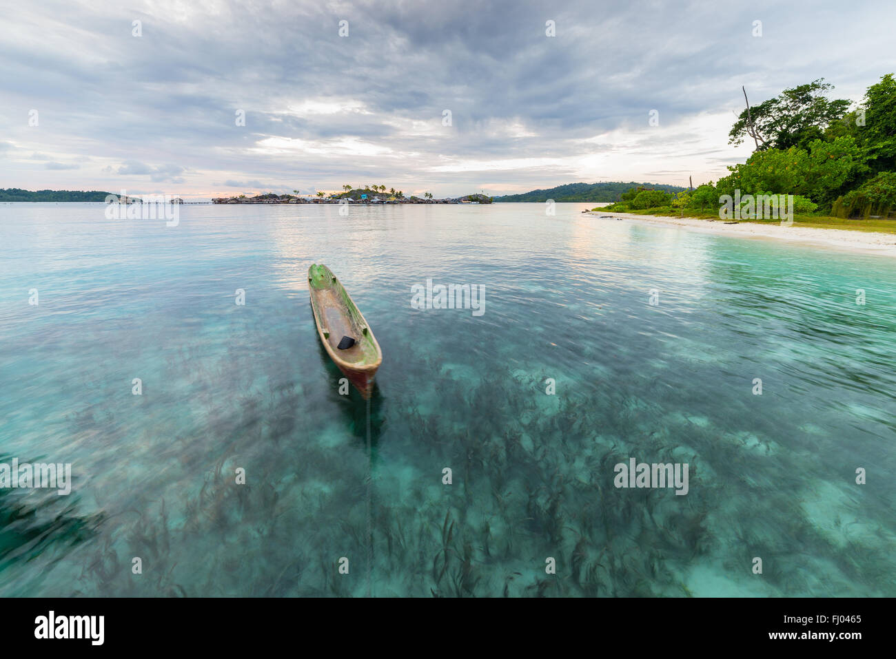 Traditional wooden canoe floating on the transparent turquoise water of ...