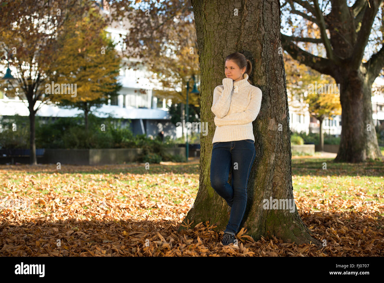 young woman in autumn park, standing near tree Stock Photo - Alamy