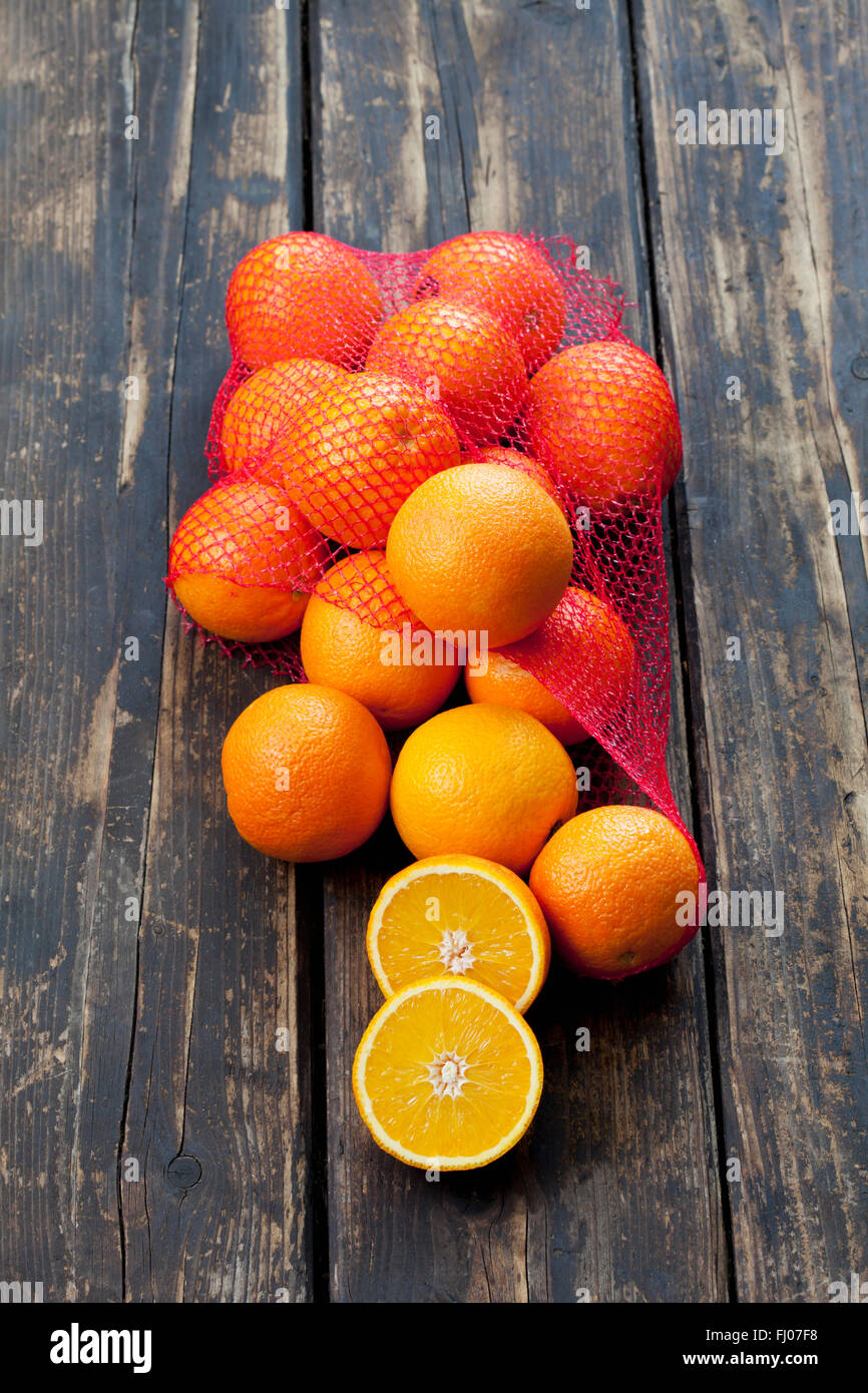 Net of oranges on dark wood Stock Photo - Alamy